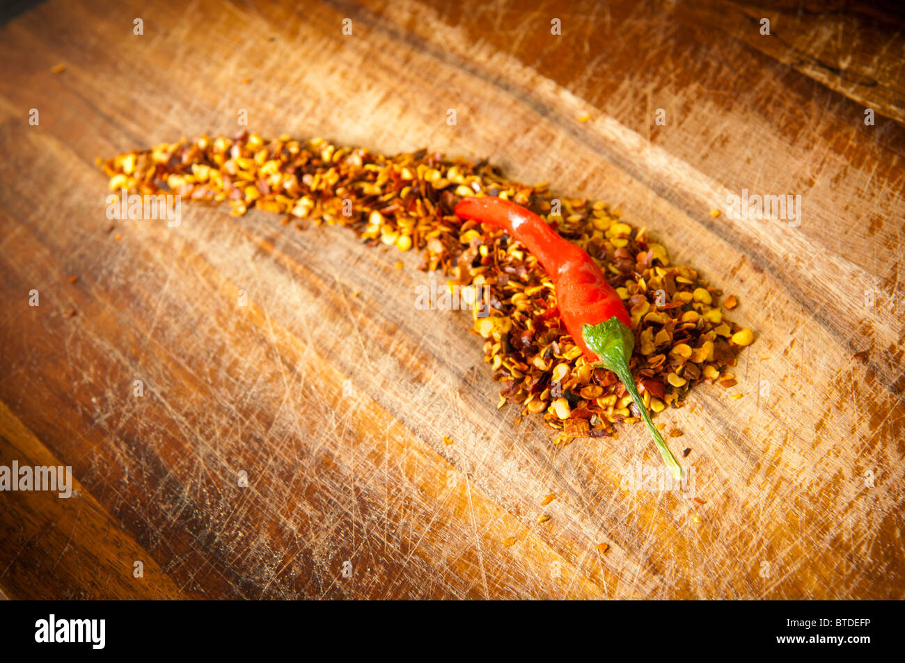 Red hot chilli concept - chilli sits atop chilli seeds shaped like a ...