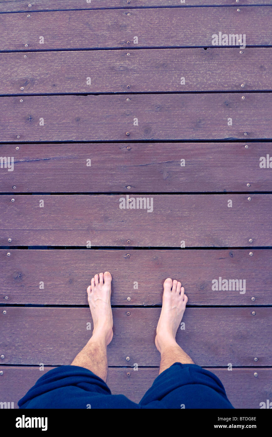 First person's perspective looking down on bare feet standing on frost ...