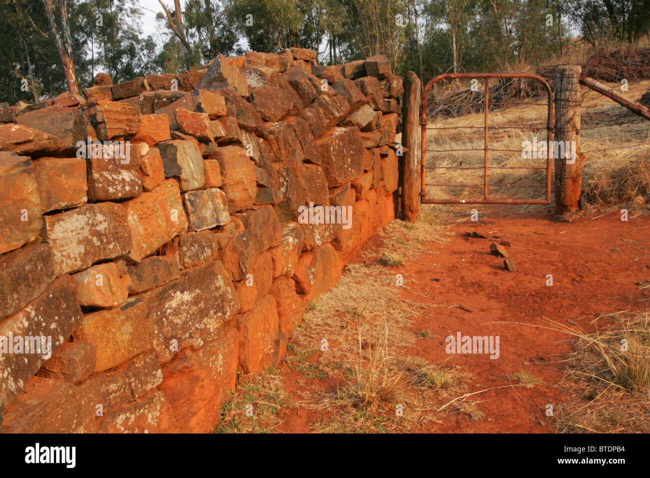 A close up of a red stone wall and a rusted gate Stock Photo - Alamy