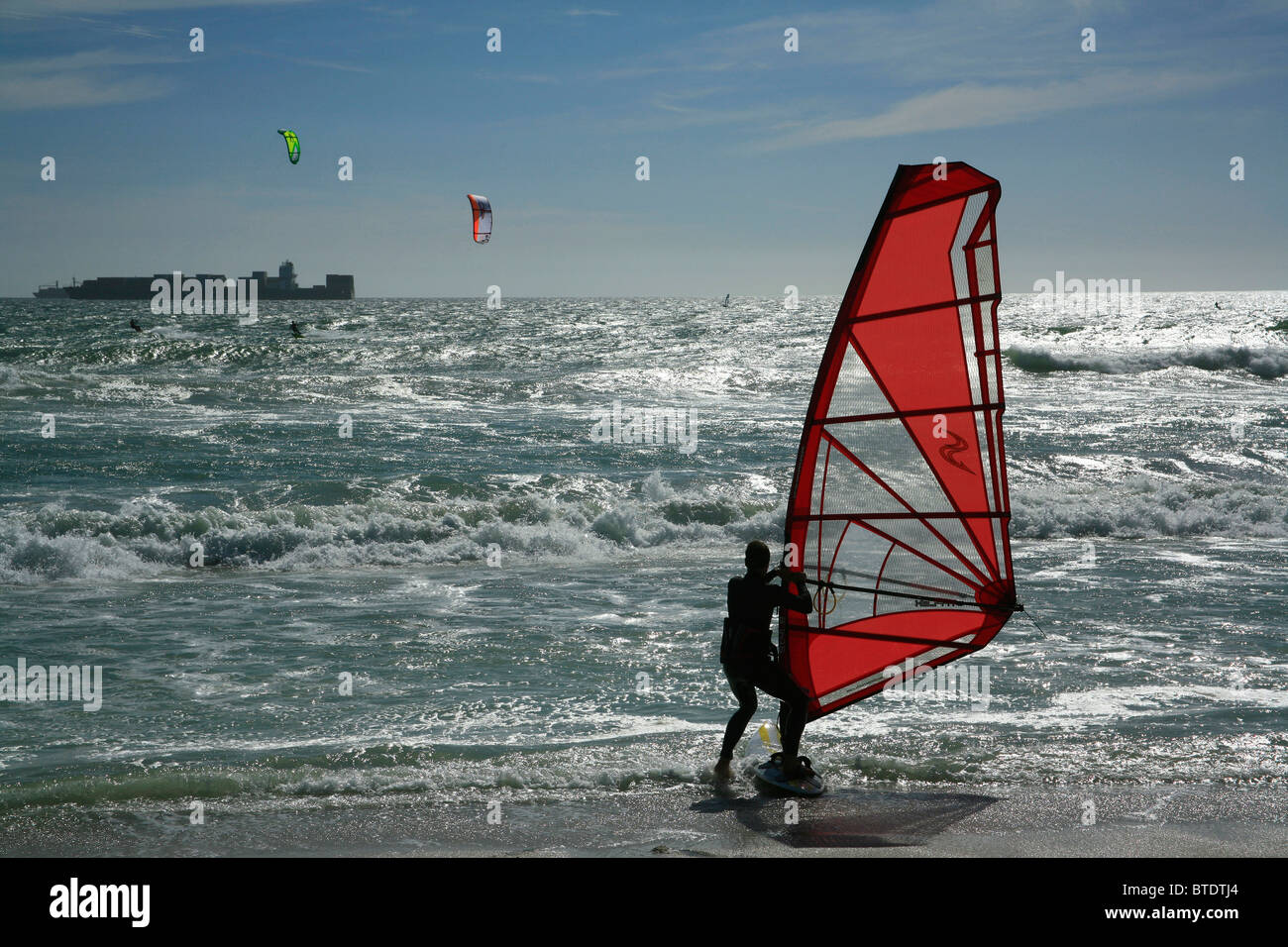 Windsurfer in the surf and kite surfers over the ocean at Blouberg ...