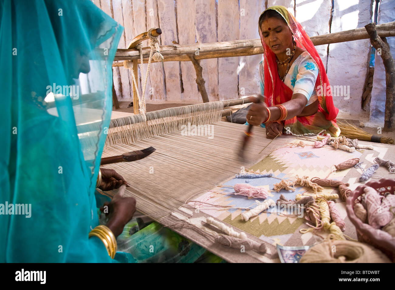Indian women weaves a dhurrie on a traditional loom using a typical ...