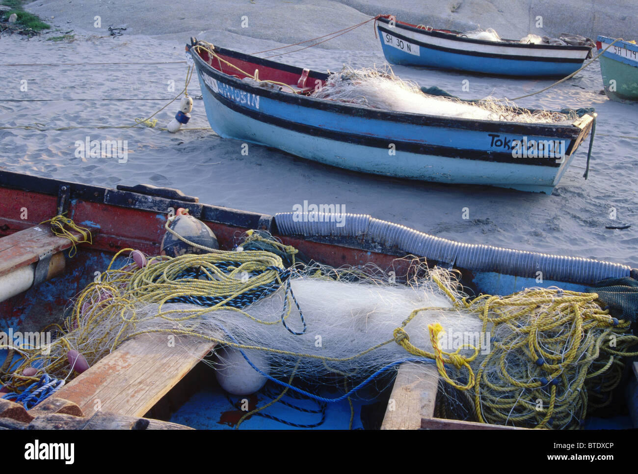 Fishing boats with their fine nets lie pulled up on the beach at low ...