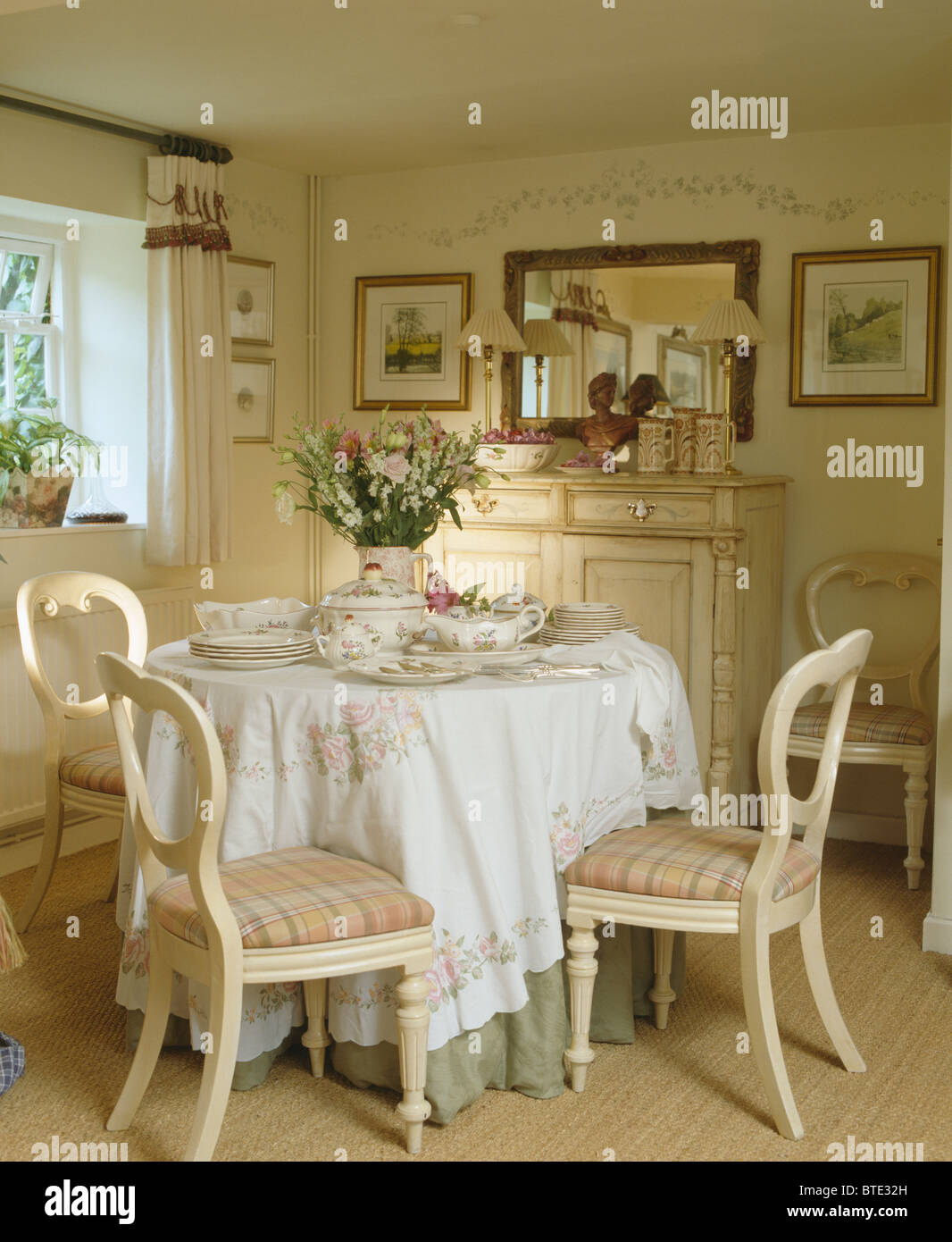 Cream chairs with checked upholstered seats at circular table with ...