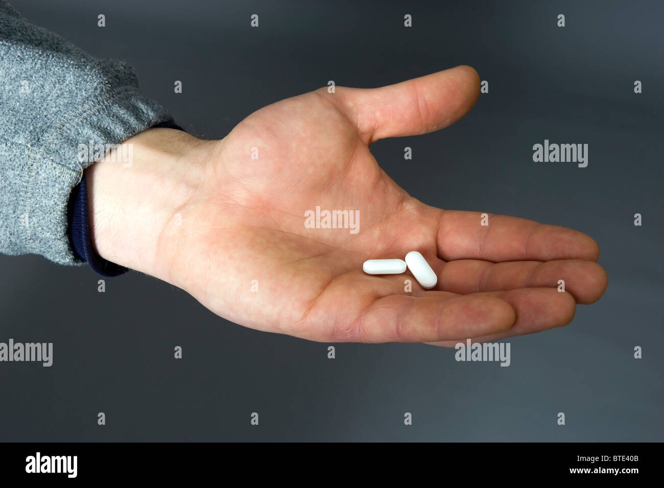Mans hand with 2 pills Stock Photo - Alamy