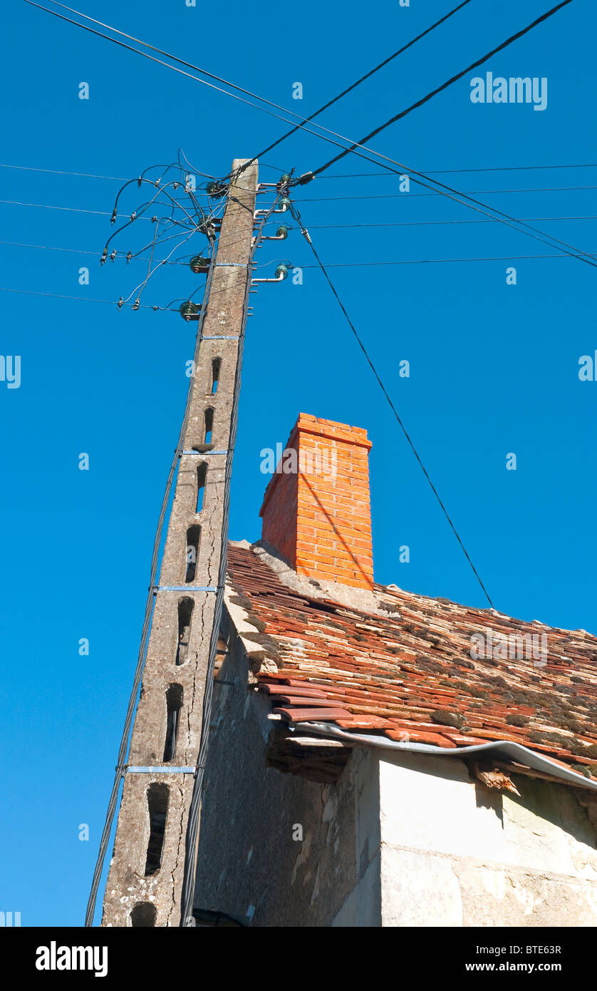 Old concrete telephone post leaning near house wall - France Stock ...