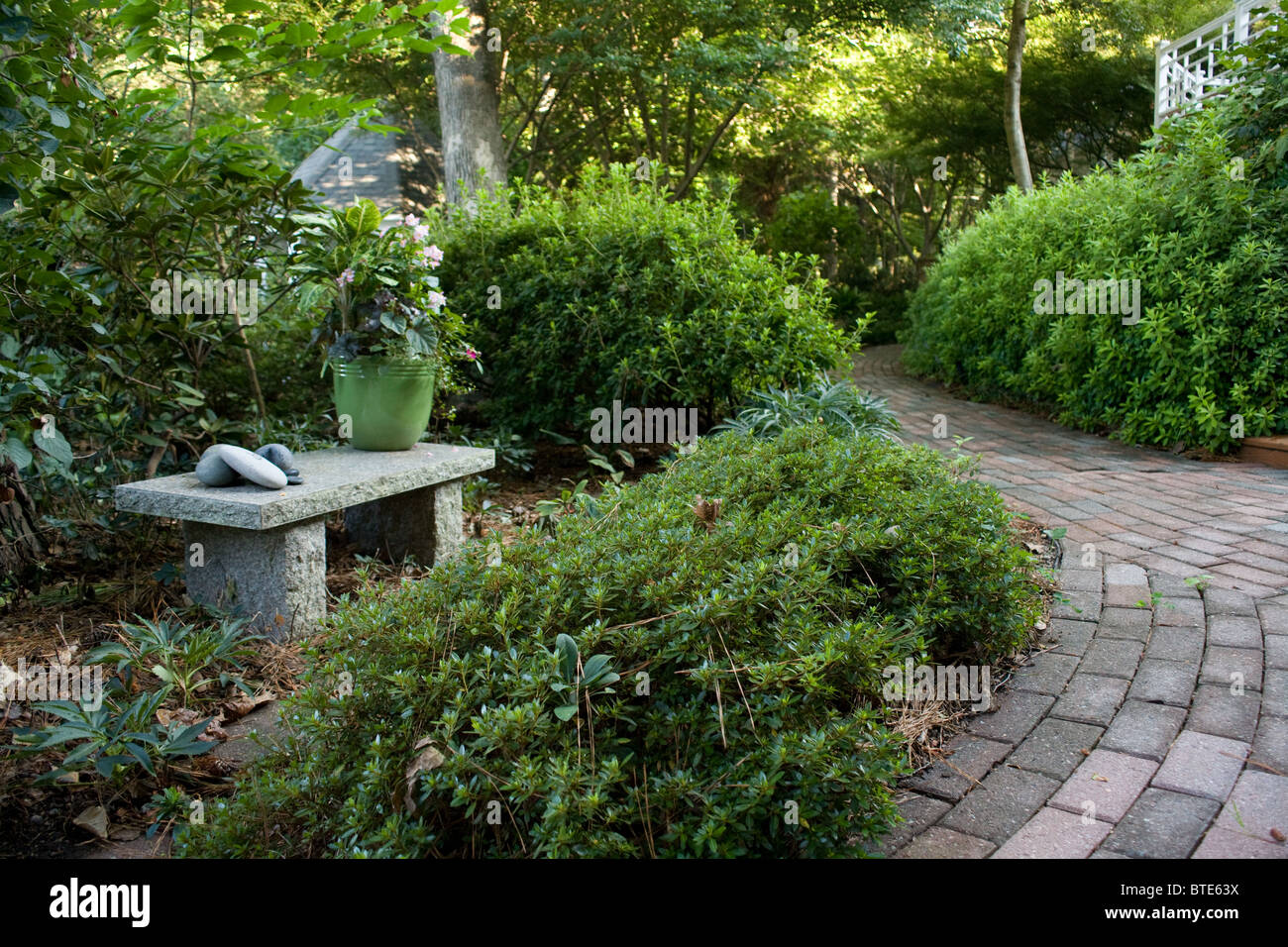 Brick path leading through the gardens past a resting spot Stock Photo ...