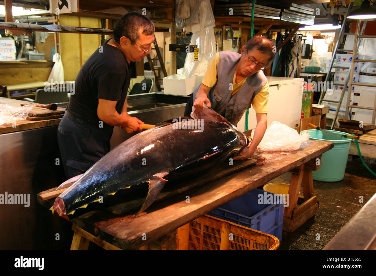 Huge blue fin tuna being cut with a long sword in Tsukiji fish market ...