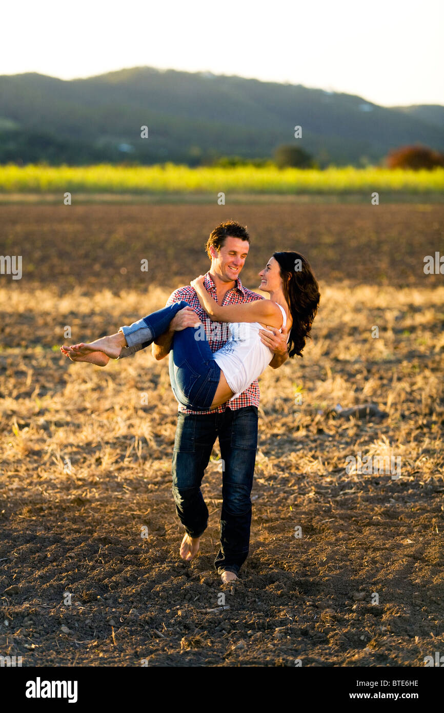 Man carrying his female partner in his arms both looking at each other ...