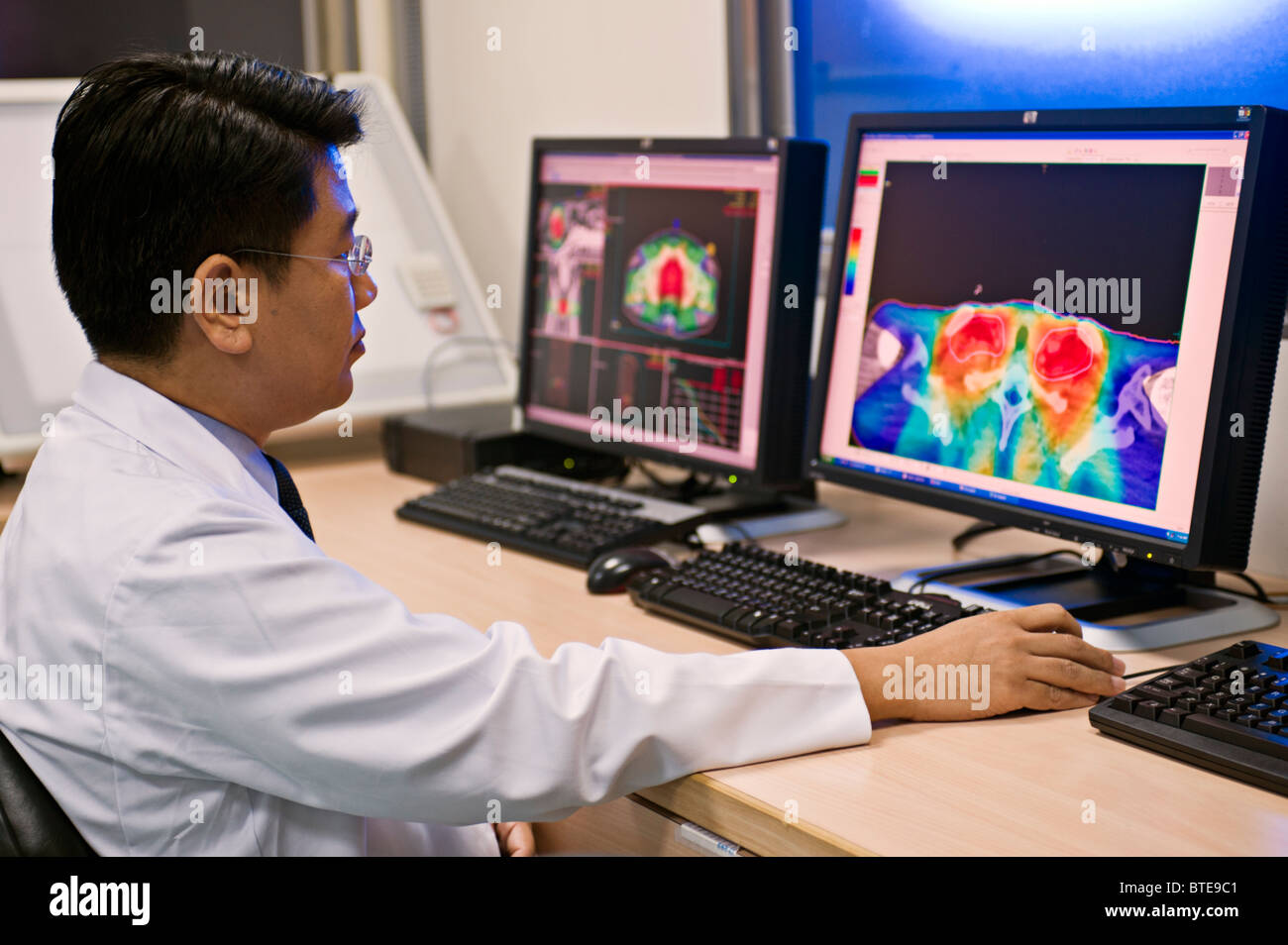 Doctor viewing CT scan results images on computer monitor in hospital ...