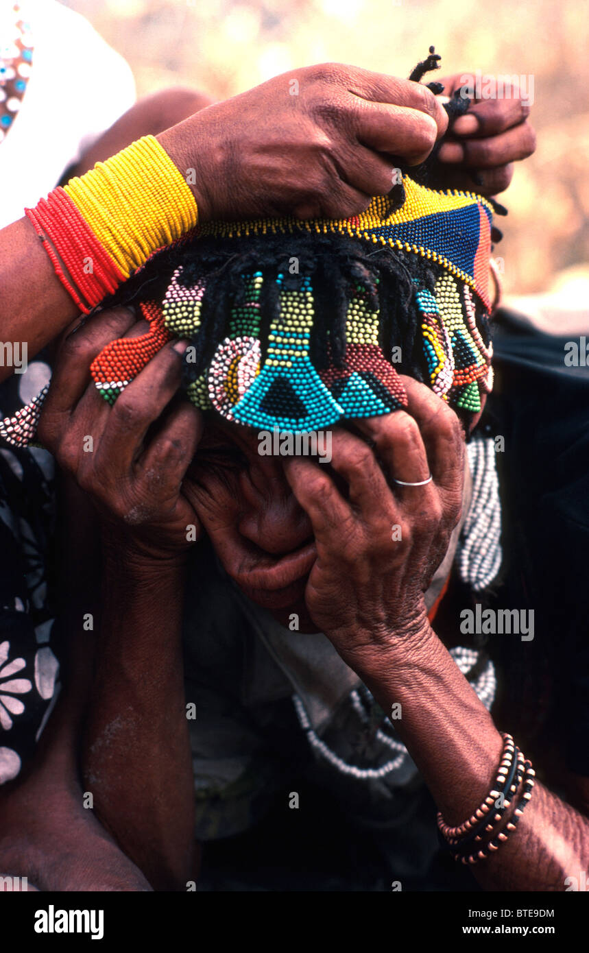 Kung Bushman woman decorating her elderly mother's hair with beads ...
