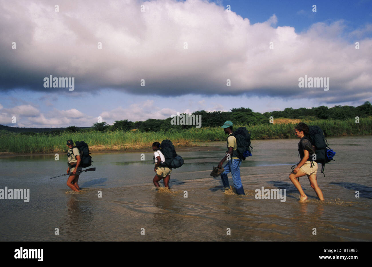 Hikers wade across the White Umfolozi River in the Umfolozi Game ...