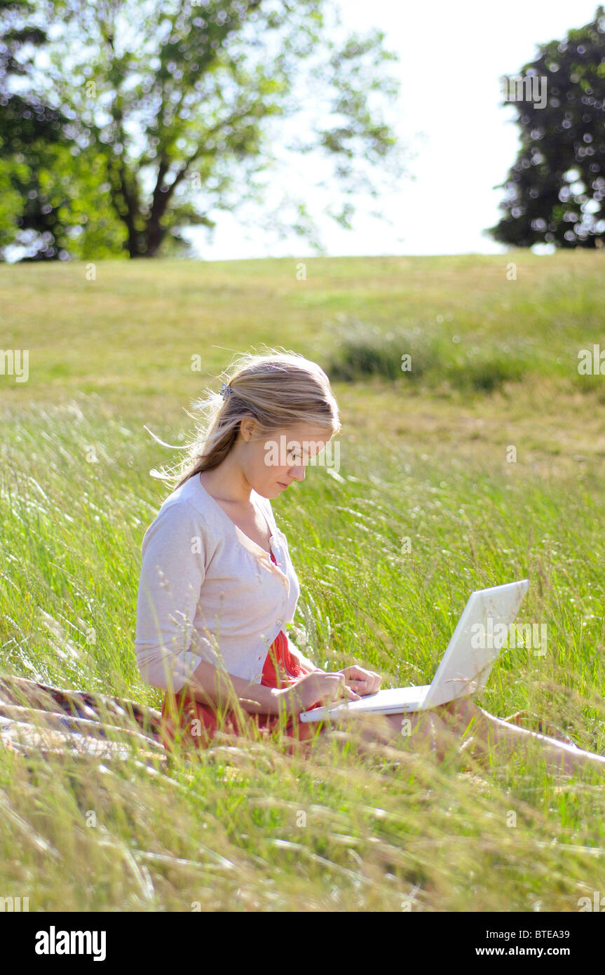 Young woman using laptop computer in park Stock Photo - Alamy