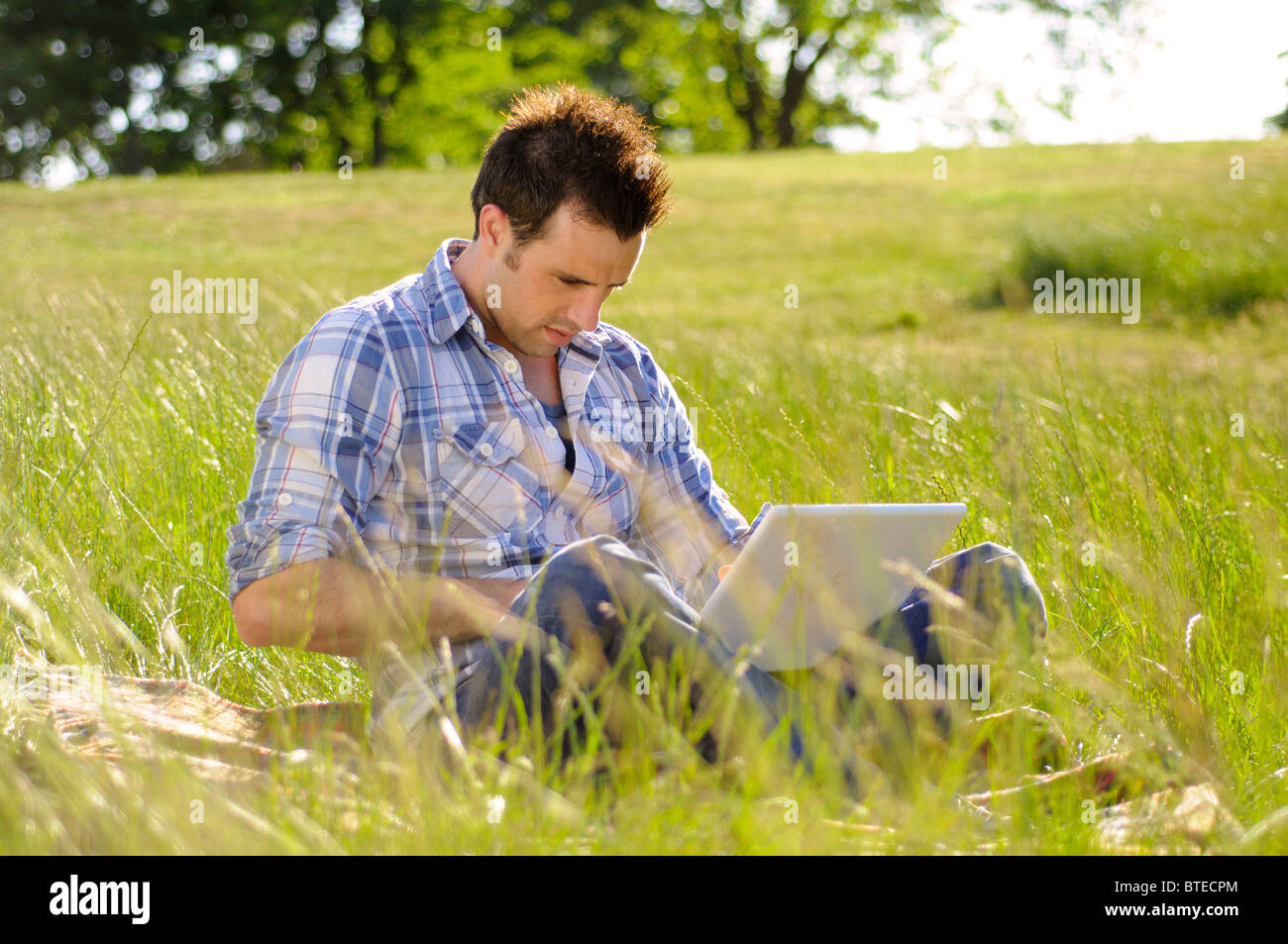 Young man using laptop computer in park Stock Photo - Alamy