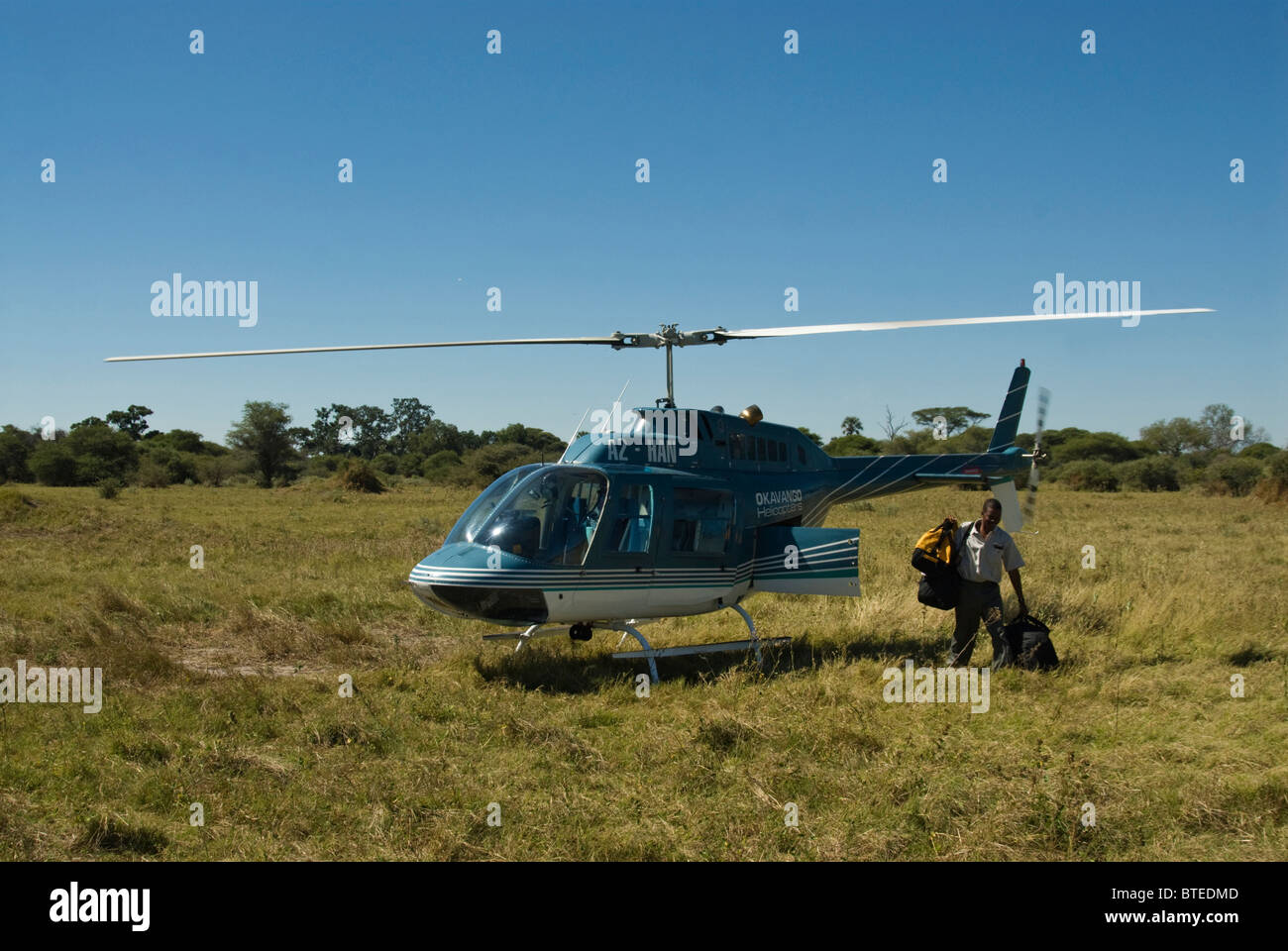 A helicopter with a porter carrying the suitcases for tourists arriving ...