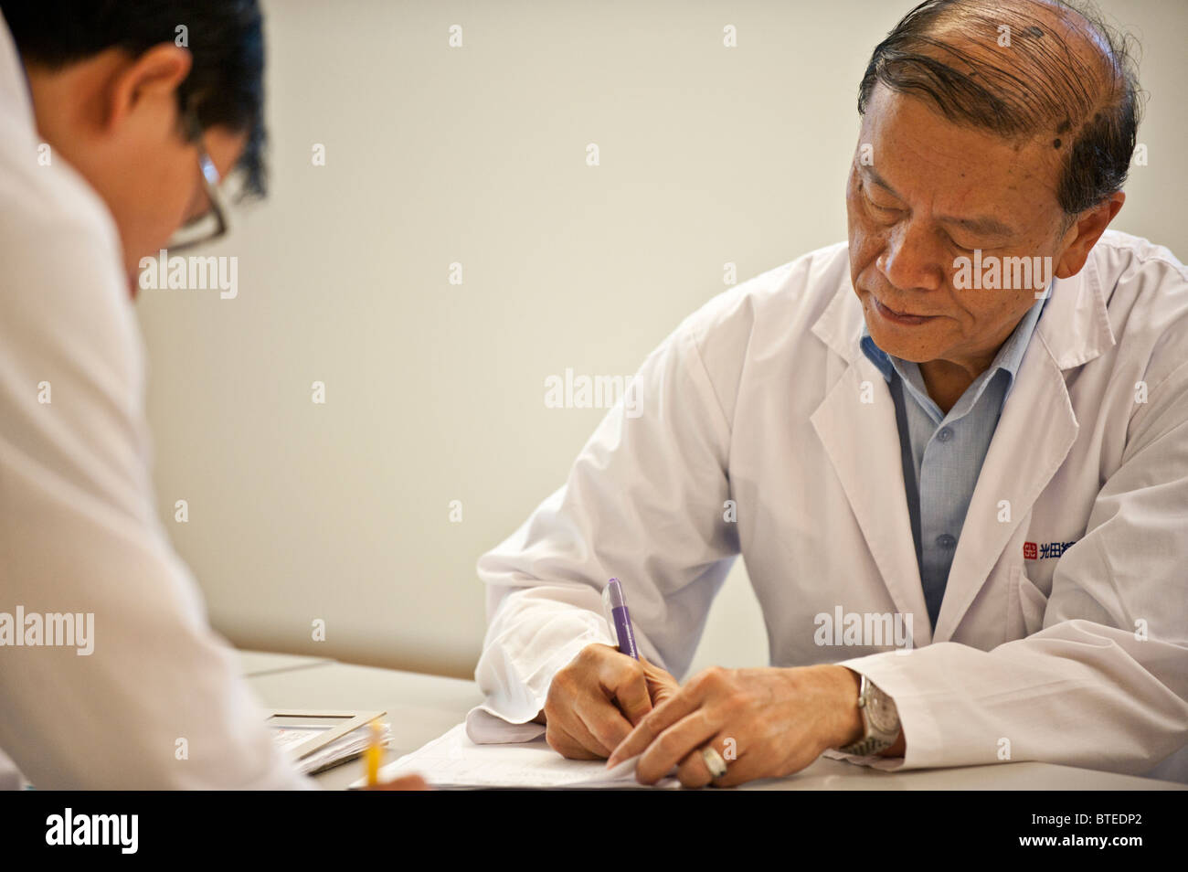 Doctors working and writing charts at desk in hospital Stock Photo - Alamy