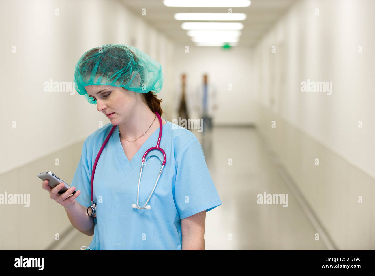 Nurse in hospital corridor using cell phone Stock Photo - Alamy