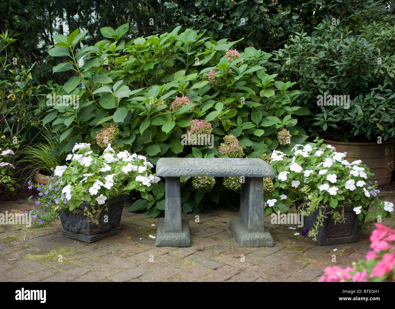 Stone bench and potted plants in the brick courtyard Stock Photo - Alamy