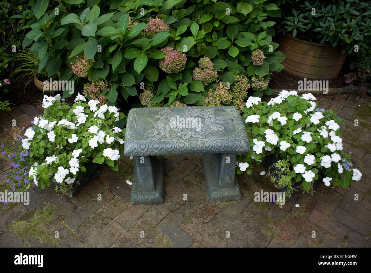 Stone bench and potted plants in the brick courtyard Stock Photo - Alamy
