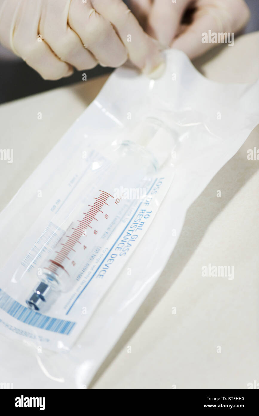 Healthcare worker opening sterile package containing medical syringe ...