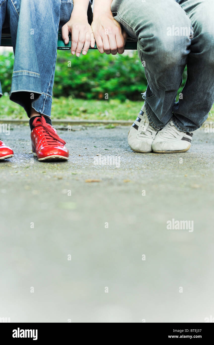 Two people sitting on a bench, hands touching Stock Photo - Alamy