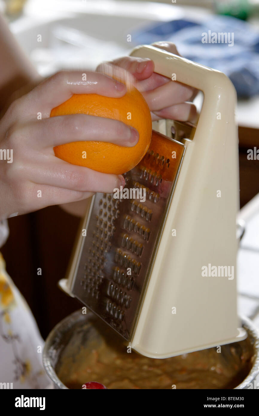 person grating orange peel on grater close up Stock Photo - Alamy