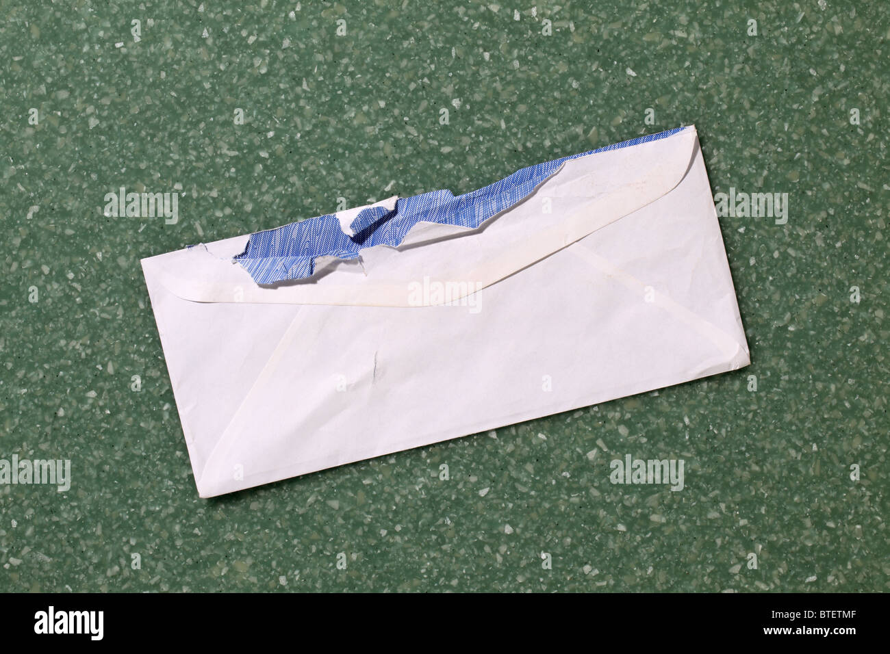 A used postal mailing envelope torn open. Green speckled counter top ...