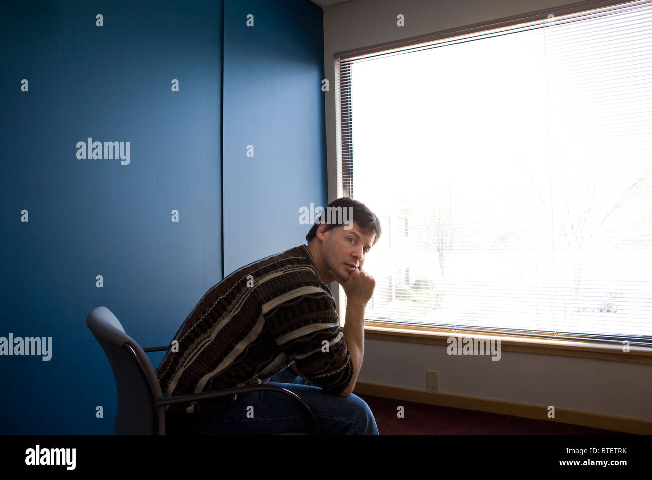 Man sitting in front of an office window Stock Photo - Alamy