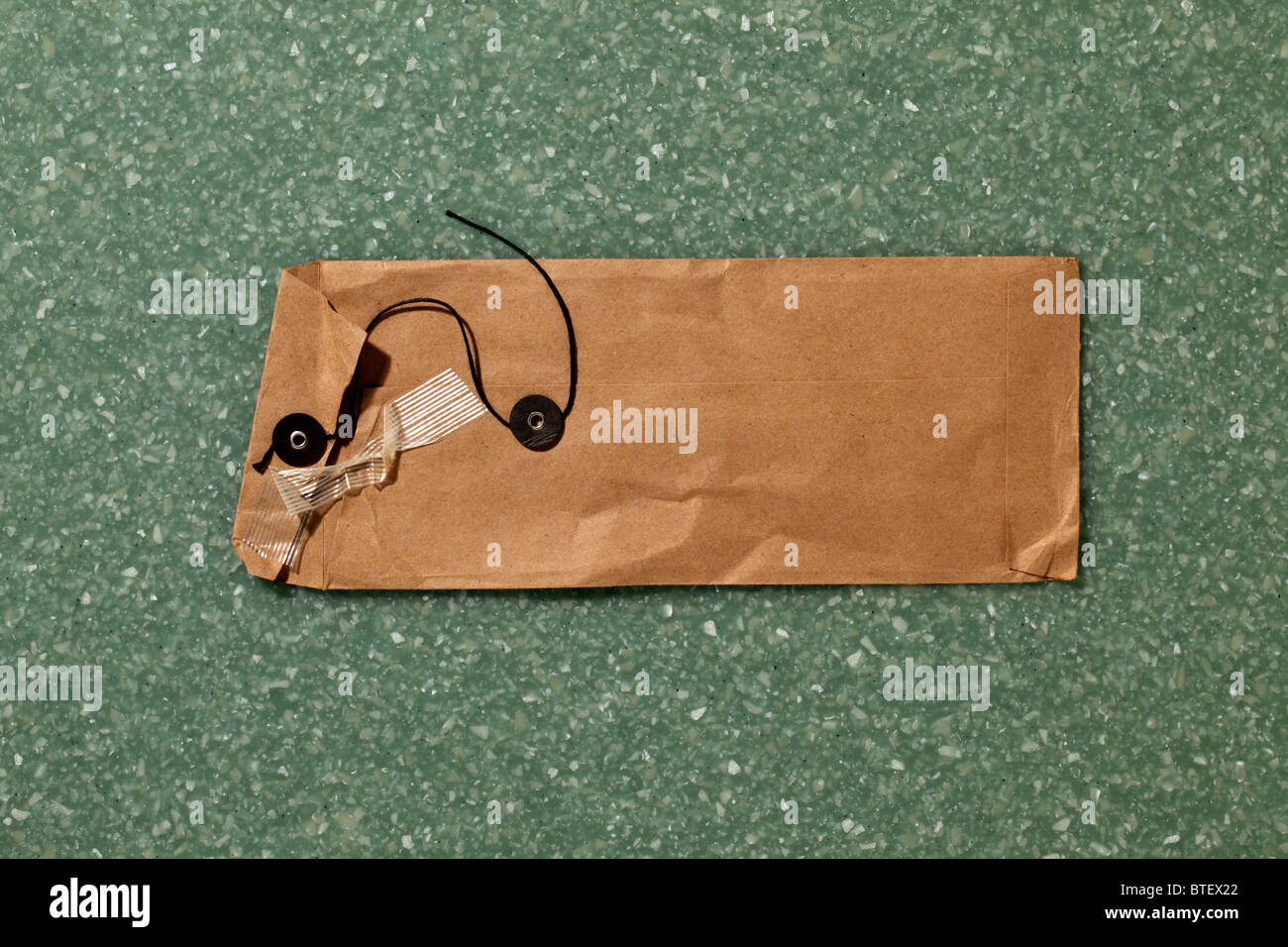 A used postal mailing envelope torn open. Green speckled counter top ...