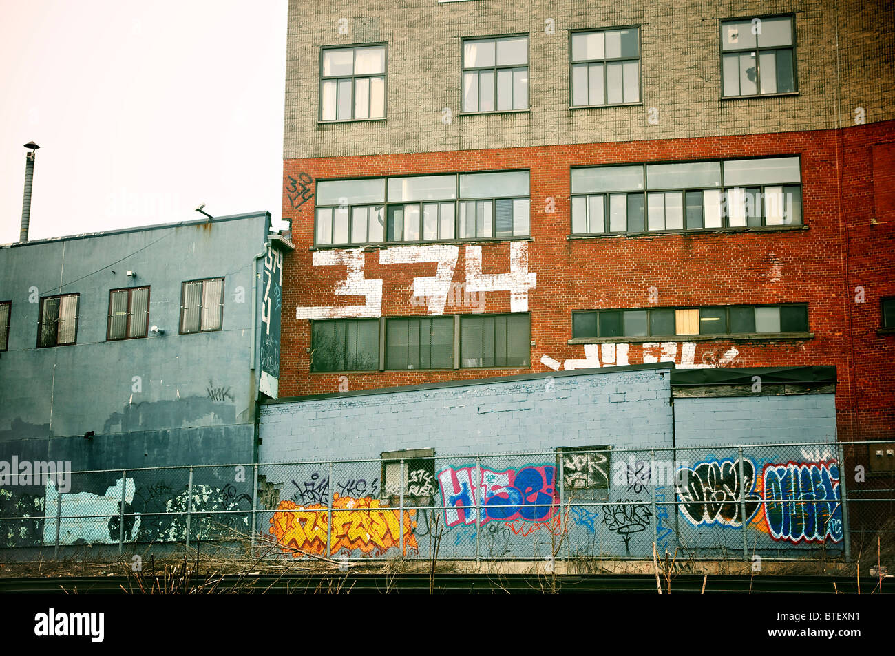 Graffiti on old industrial building behind steel fence, Montreal ...
