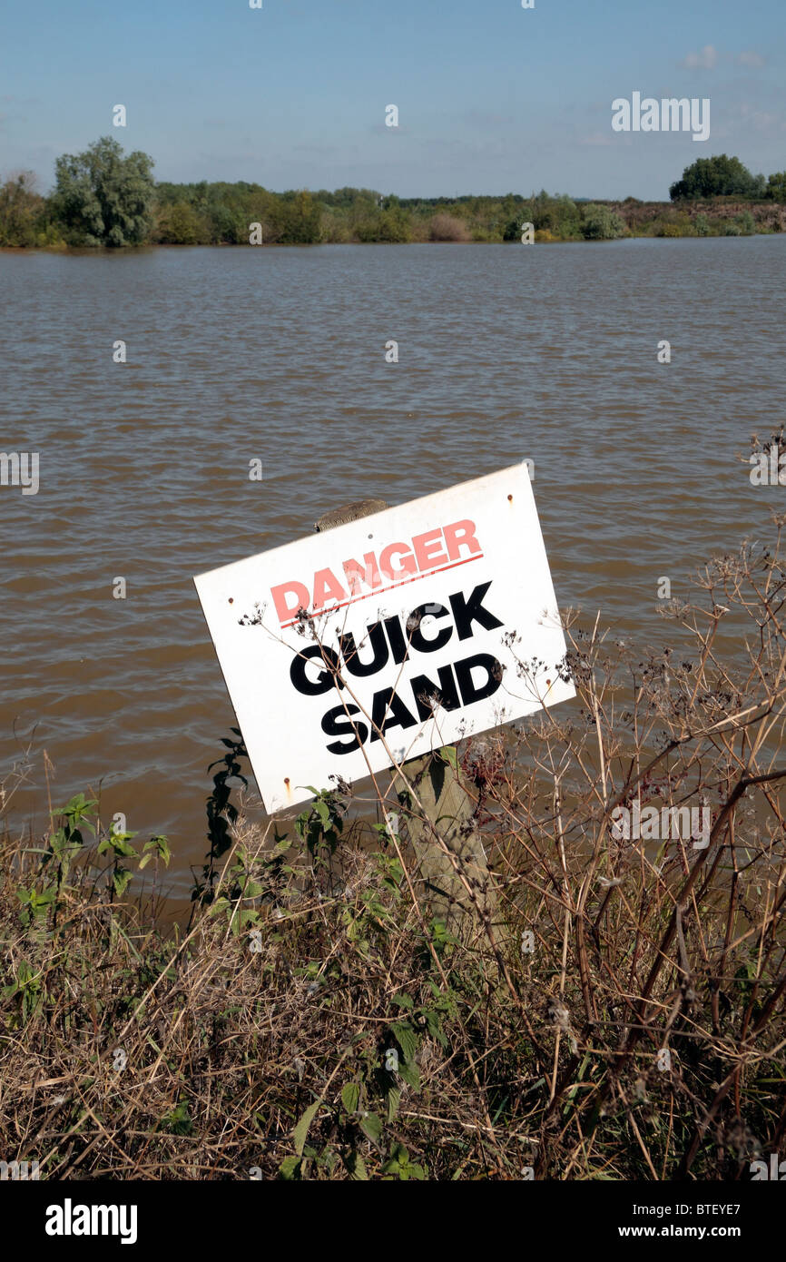 A 'Quicksand' warning sign at the edge of a lake in England, UK Stock ...