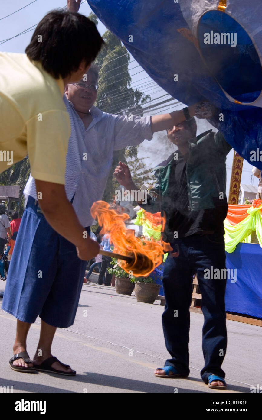 Men are using a torch to heat a hot air balloon at the Loi Kratong ...
