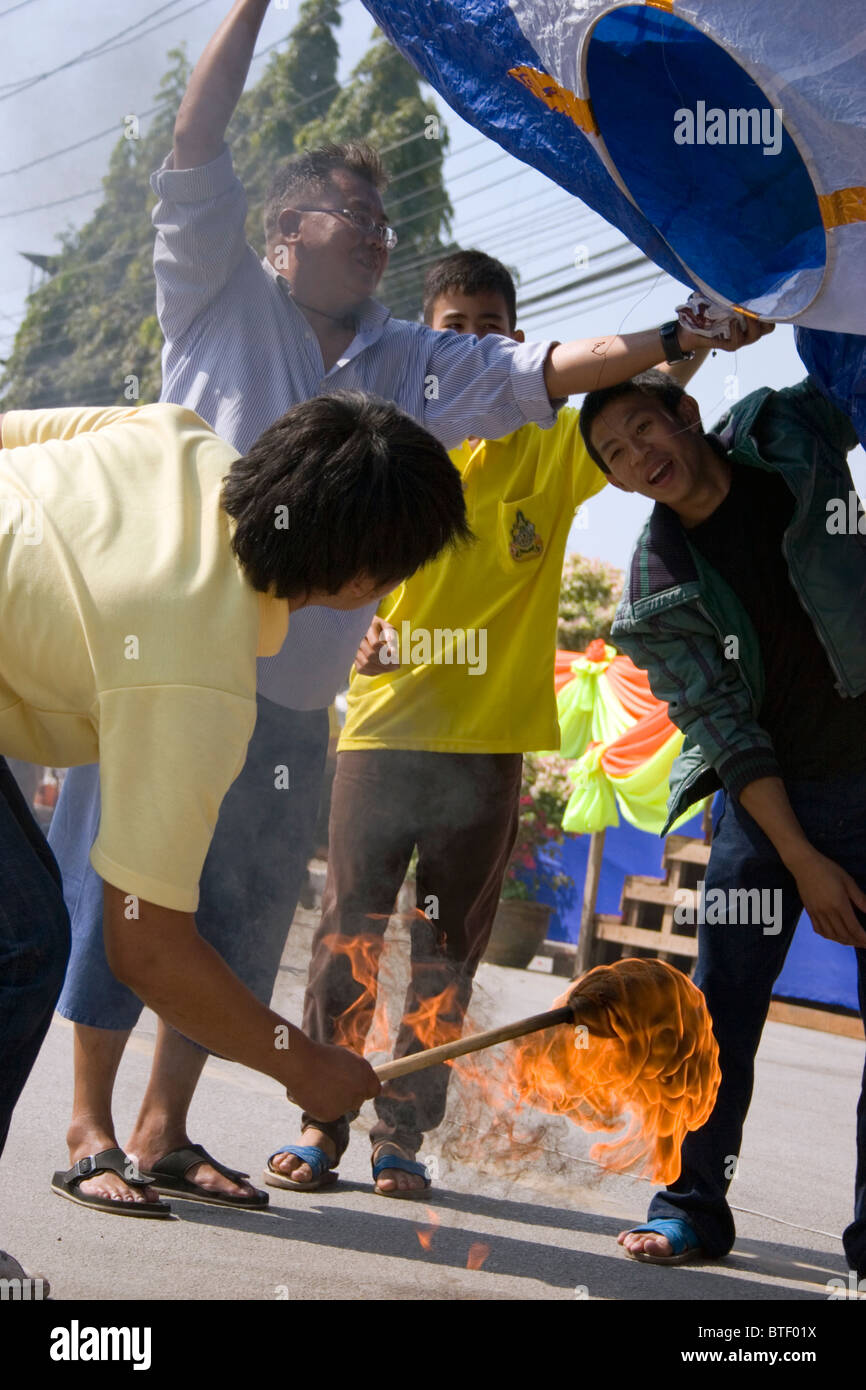 Men are using a torch to heat a hot air balloon at the Loi Kratong ...