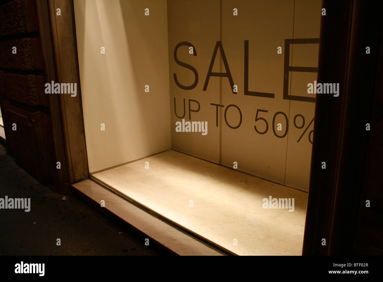 sales sign in shop window at night Stock Photo - Alamy