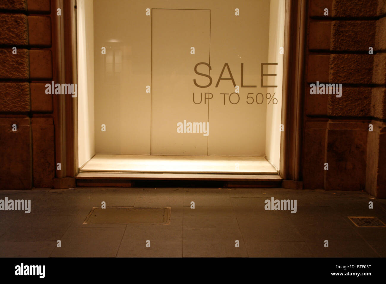 sales sign in shop window at night Stock Photo - Alamy