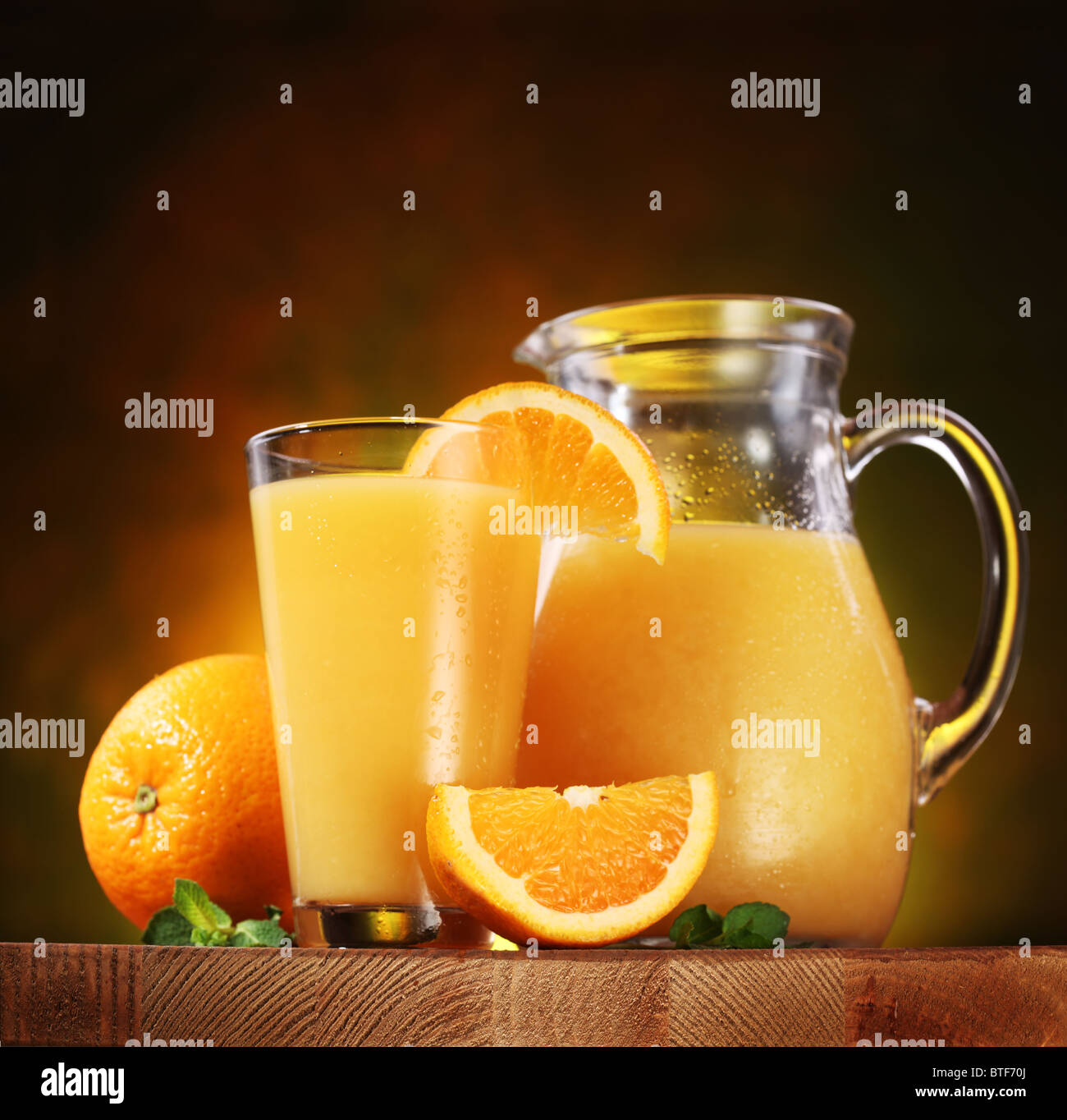 Still life: oranges, glass of juice and jug full of juice on a wooden ...