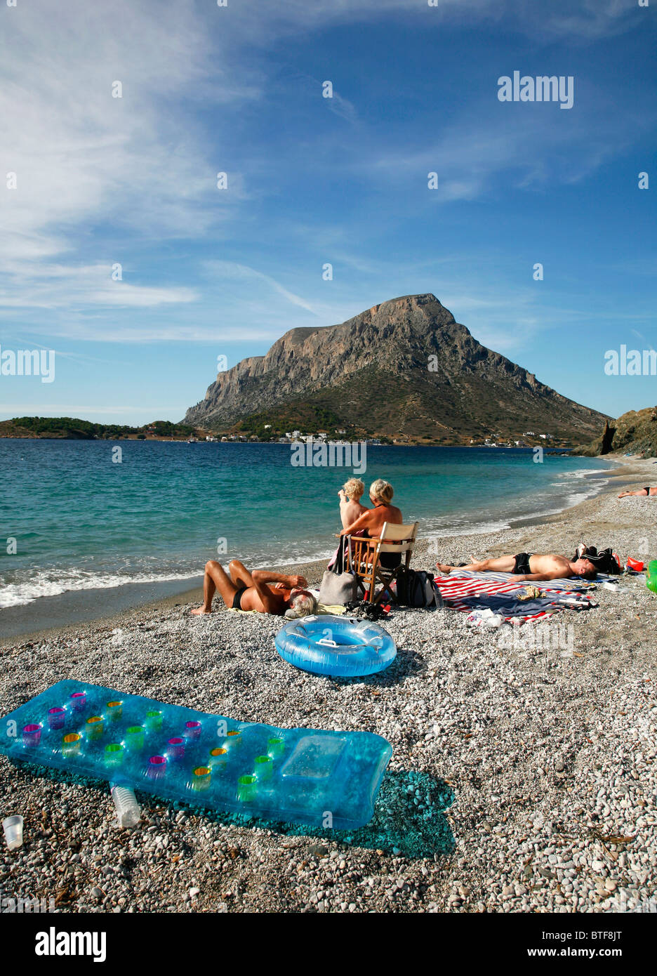 People sunbathing at Myrties beach with Telendos Island in the Front ...