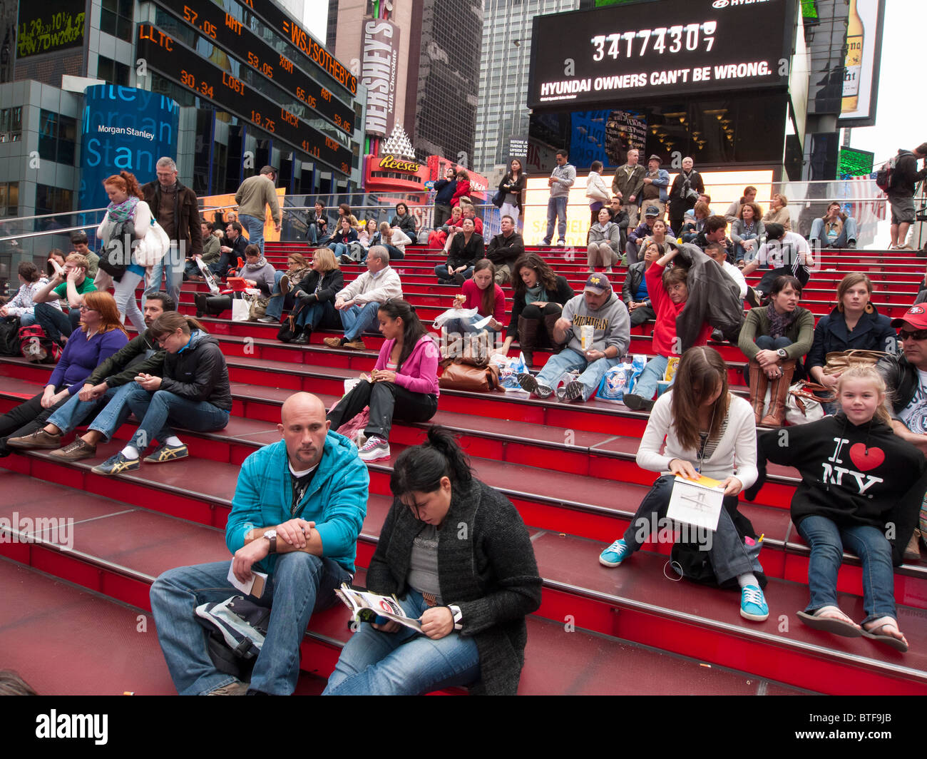 Crowd of tourists sitting on steps in Times Square Manhattan New York ...