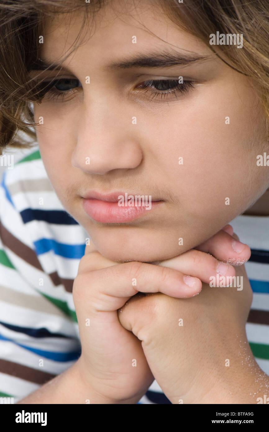 Boy with hands clasped under chin, looking down, portrait Stock Photo ...