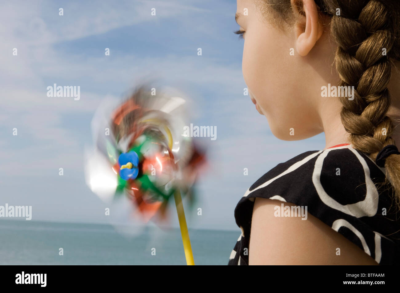 Girl blowing pinwheel Stock Photo - Alamy