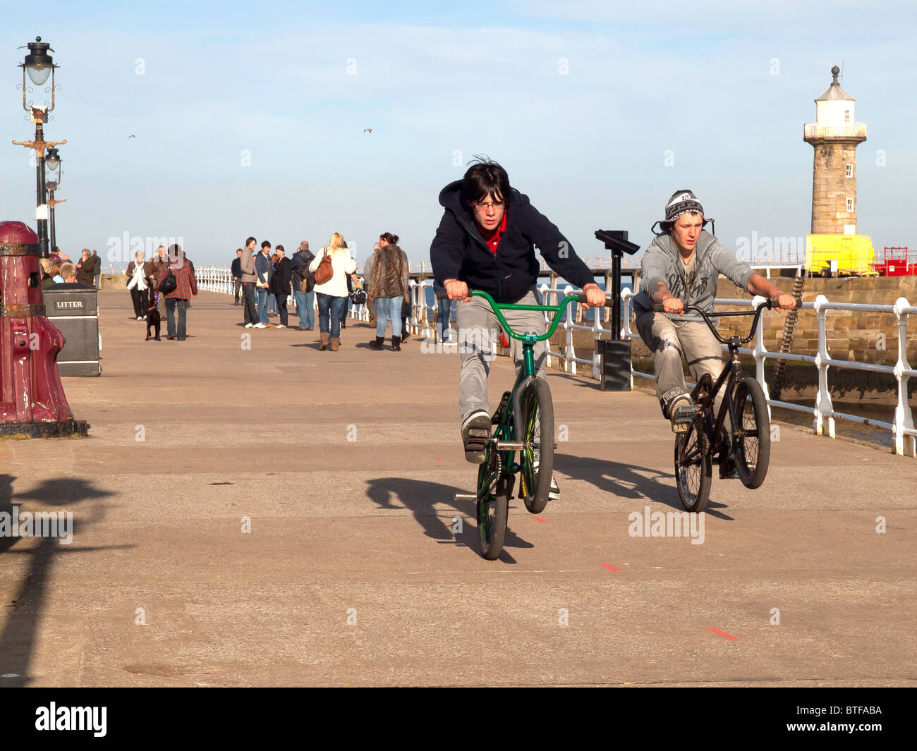 Two teen age boys on BMX stunt bicycles doing "wheelies" on Whitby Pier ...
