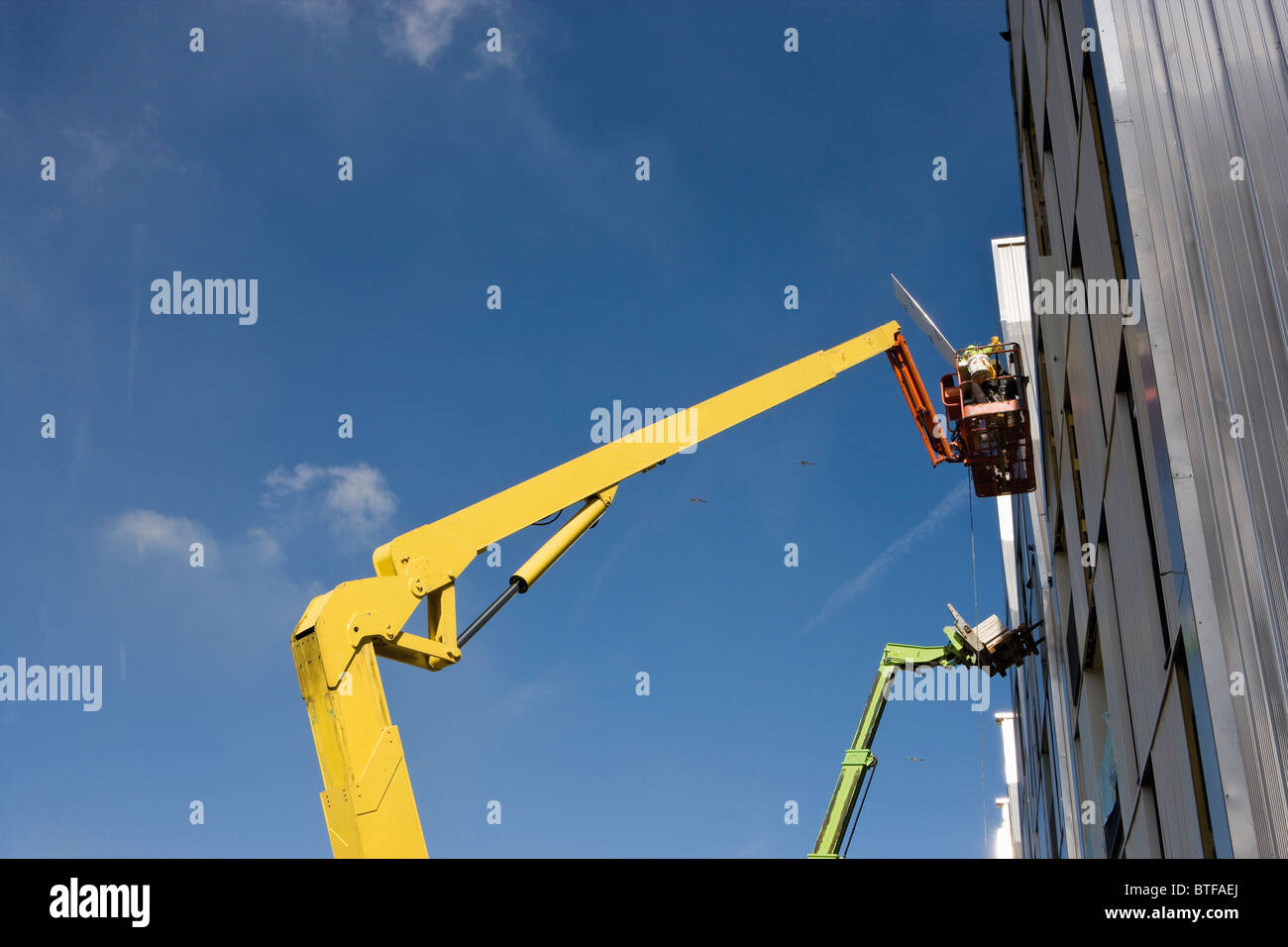 Construction workers in cherry picker bucket working on building ...