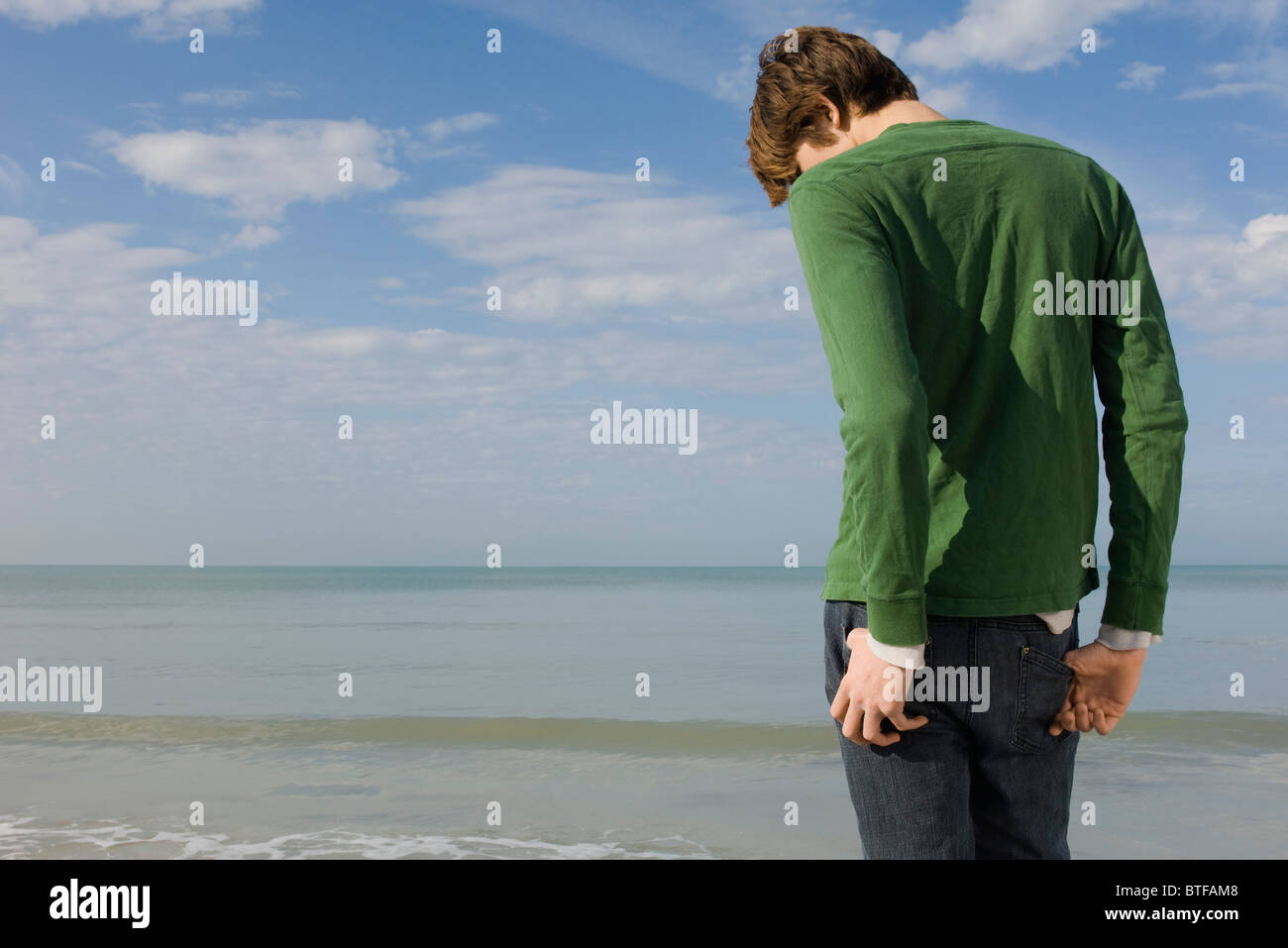 Young man standing on beach with head down, rear view Stock Photo - Alamy