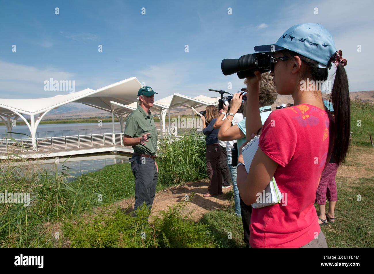 Agamon Hula Park. visitor with binoculars watching birds at lake ...
