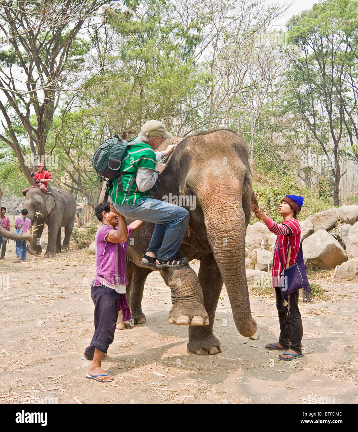 Tourist climbs aboard elephant at Patara Elephant Farm, an elephant ...