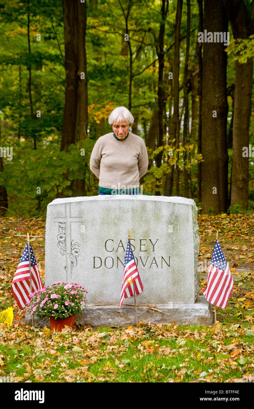 A woman visits her parents' grave in a cemetery on an autumn afternoon ...