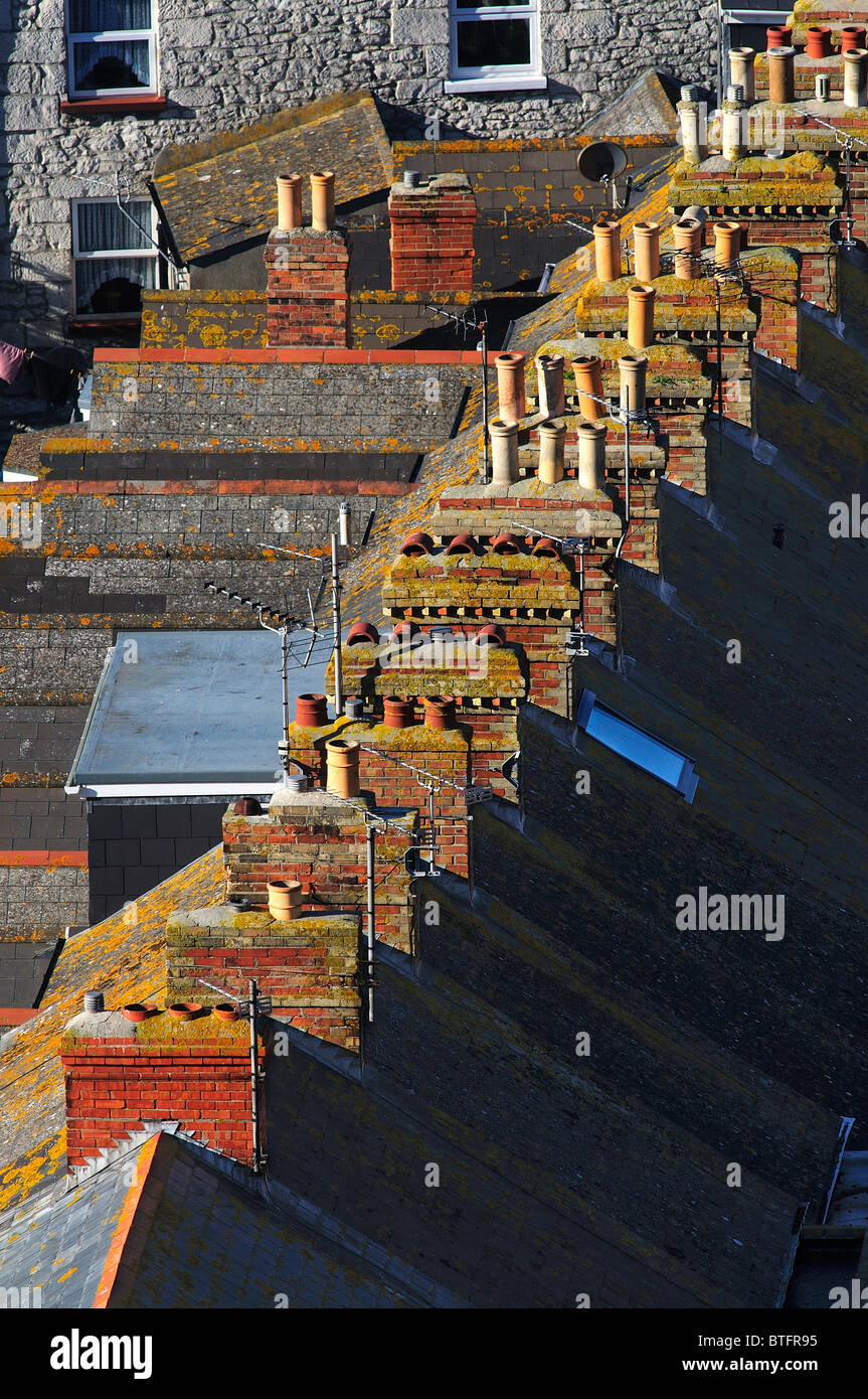 A row of chimneys and rooftops in a long terrace of houses. Dorset, UK ...