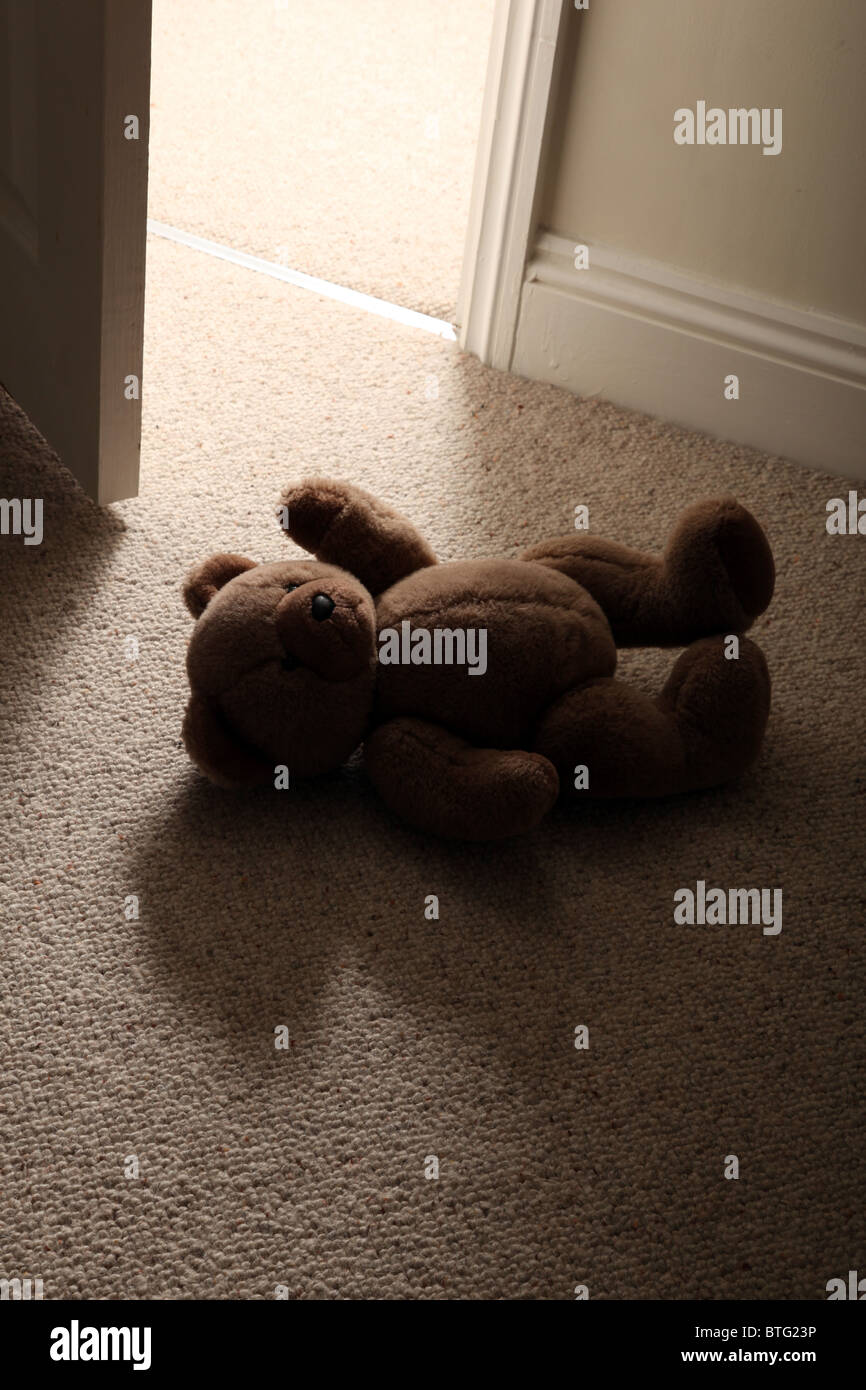 Child's teddy bear lying on the floor of a carpeted room with an open ...