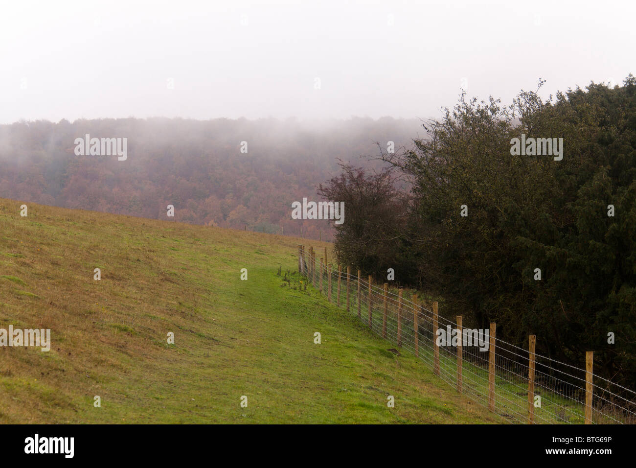 wire fencing and post in countryside with mist / low cloud rolling in ...