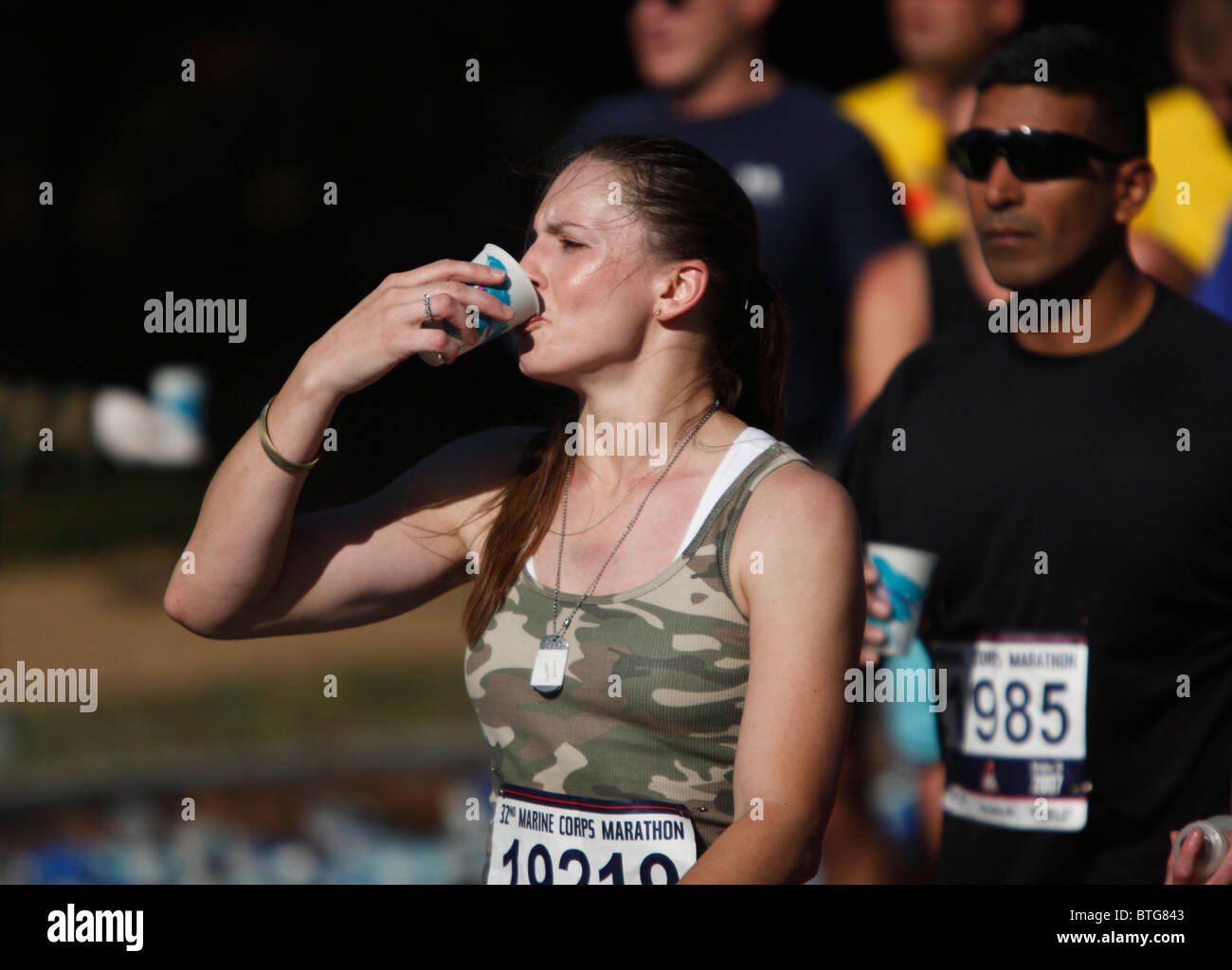 A competitor in the Marine Corps Marathon drinking a beverage at a ...