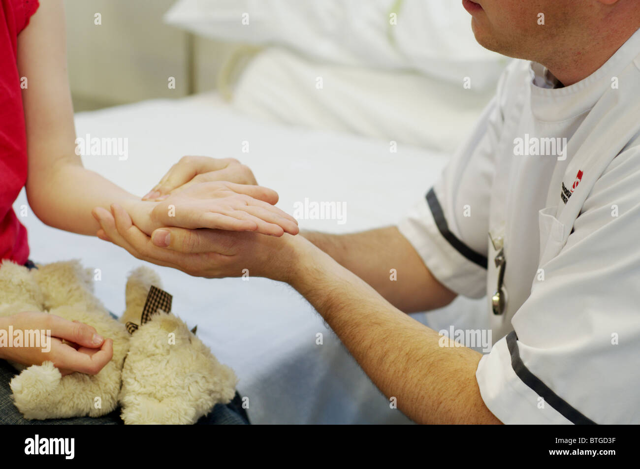 Young girl patient in hospital ward having her pulse checked by a nurse ...